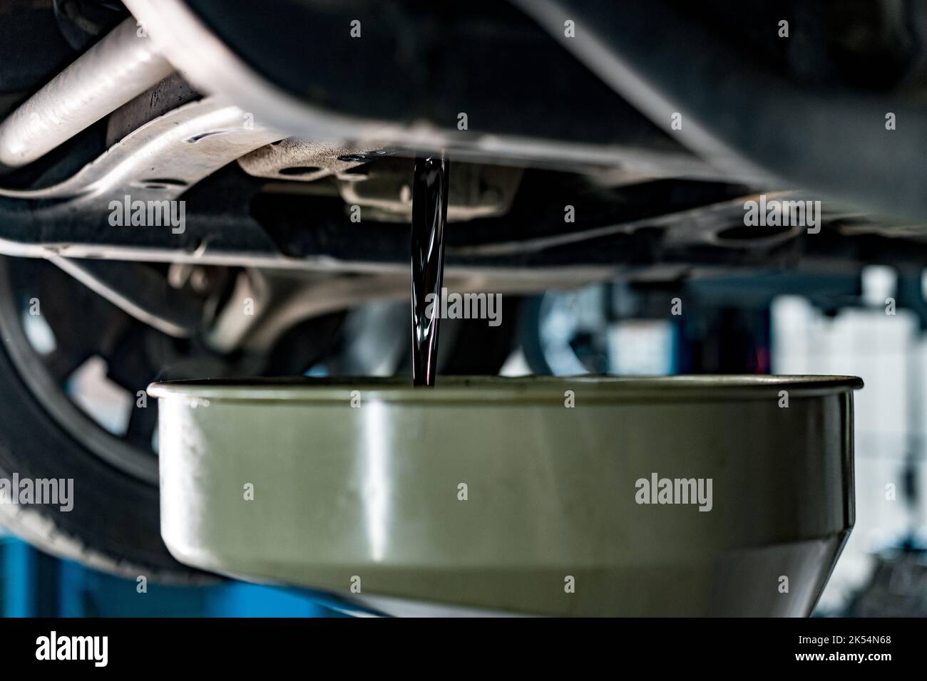 Old dirty oil pouring from the car engine in car service station close ...