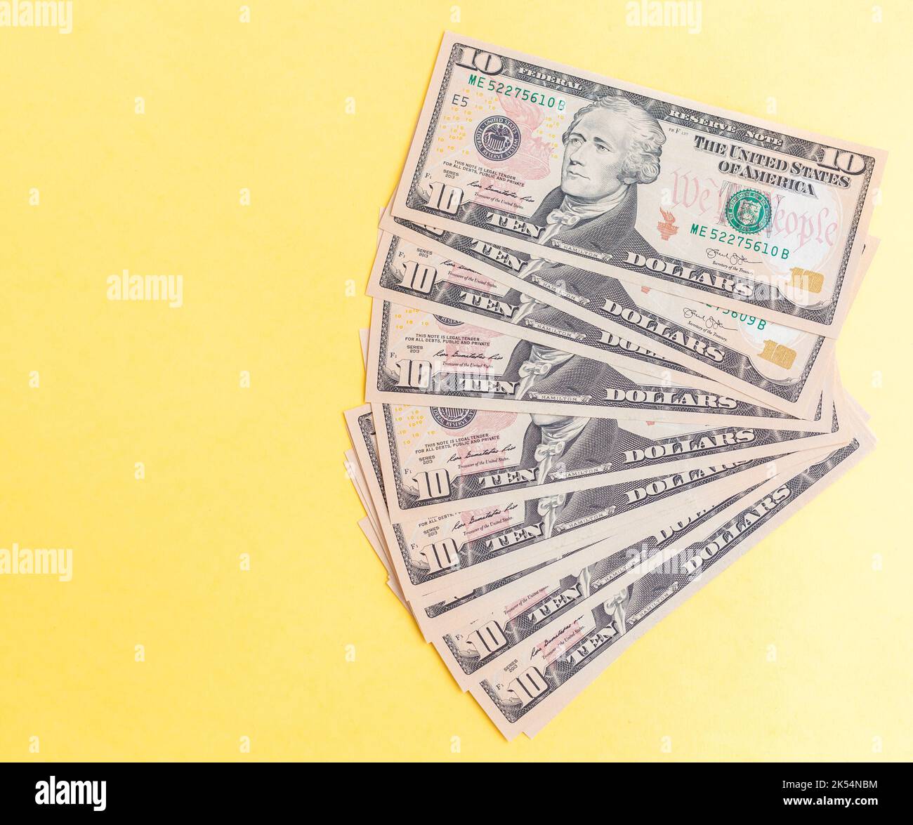 A lot of ten dollar bills are lying on a yellow background, cash paper ...
