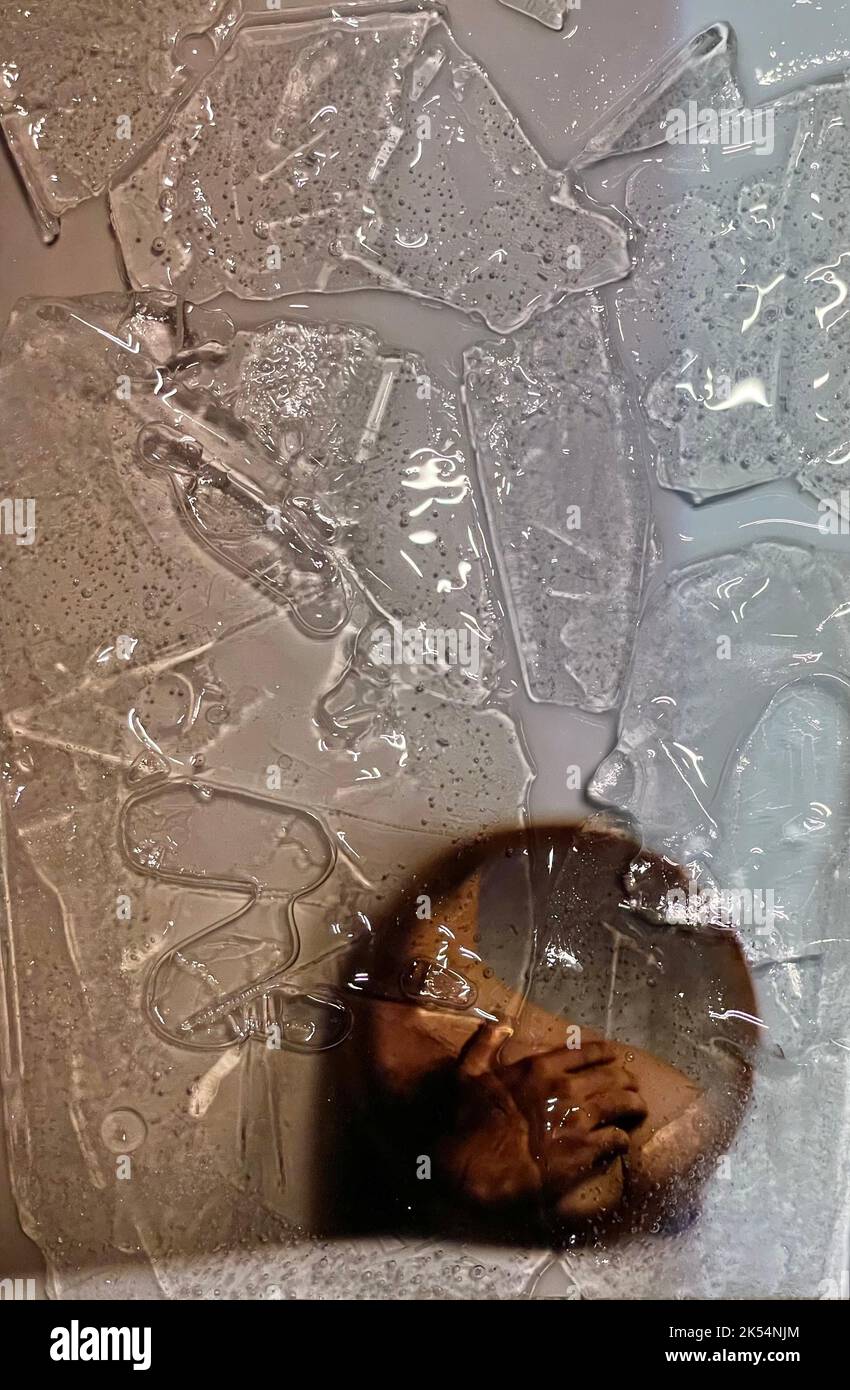 A vertical of a man's hand at his shoulder in the mirror from a melting ...