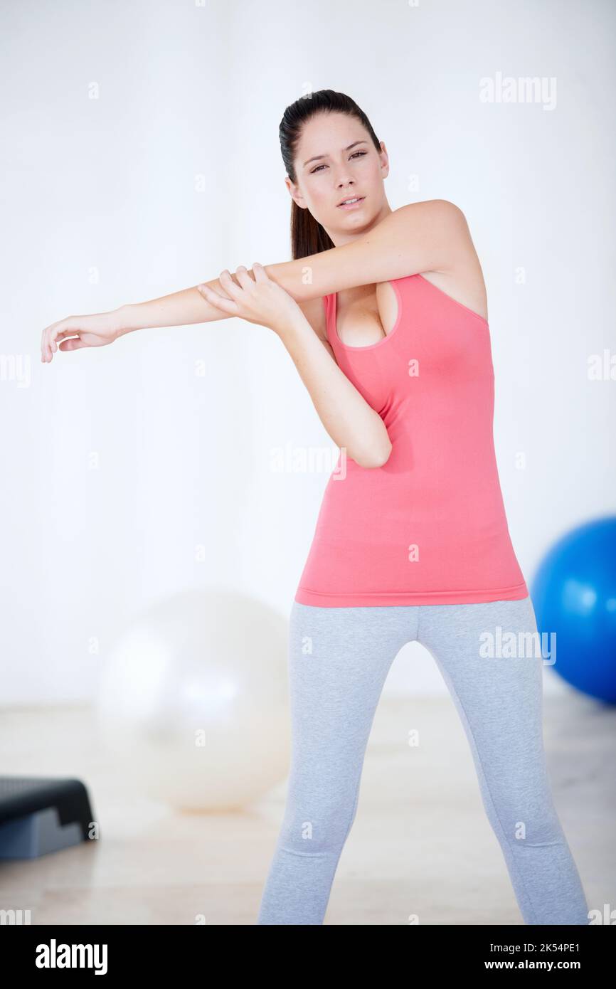 Getting ready to gym. Young woman doing stretches while standing in a ...