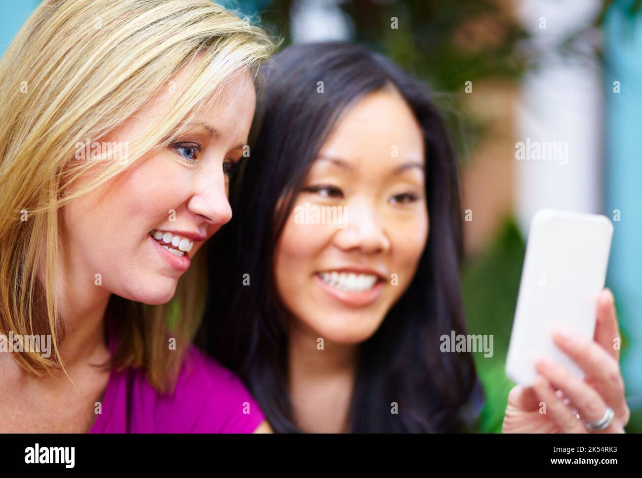 Sharing an sms with a friend. Two female friends reading a text message ...