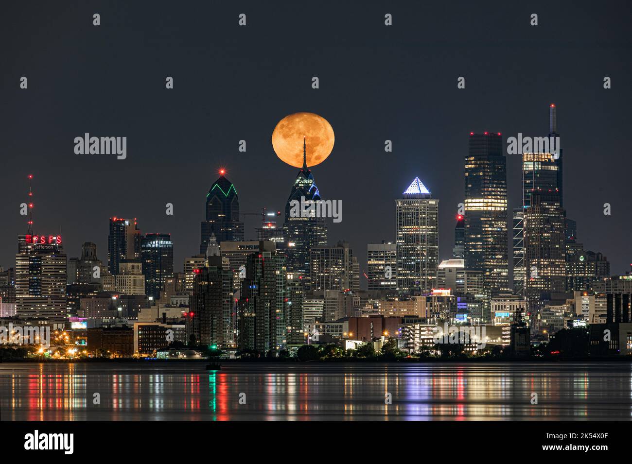 The bright yellow full moon over Philadelphia skyline reflected in the ...