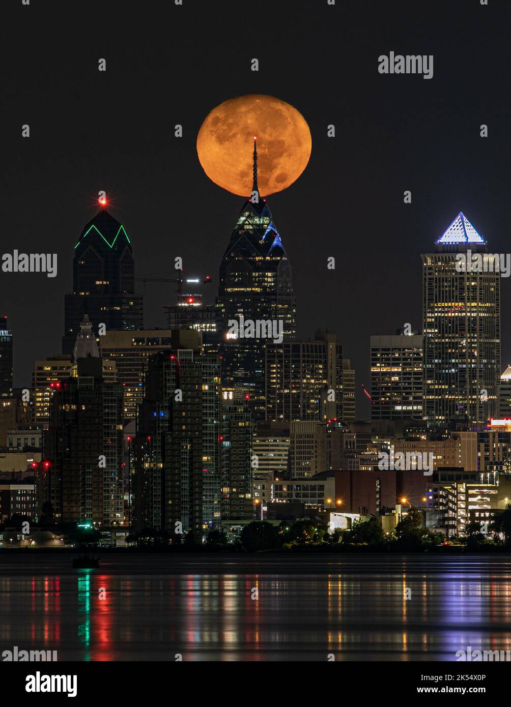 The bright yellow full moon over Philadelphia skyline reflected in the ...