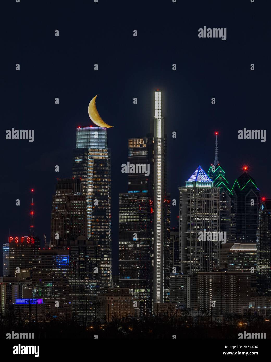 The yellow crescent moon over illuminated Philadelphia skyline at night ...