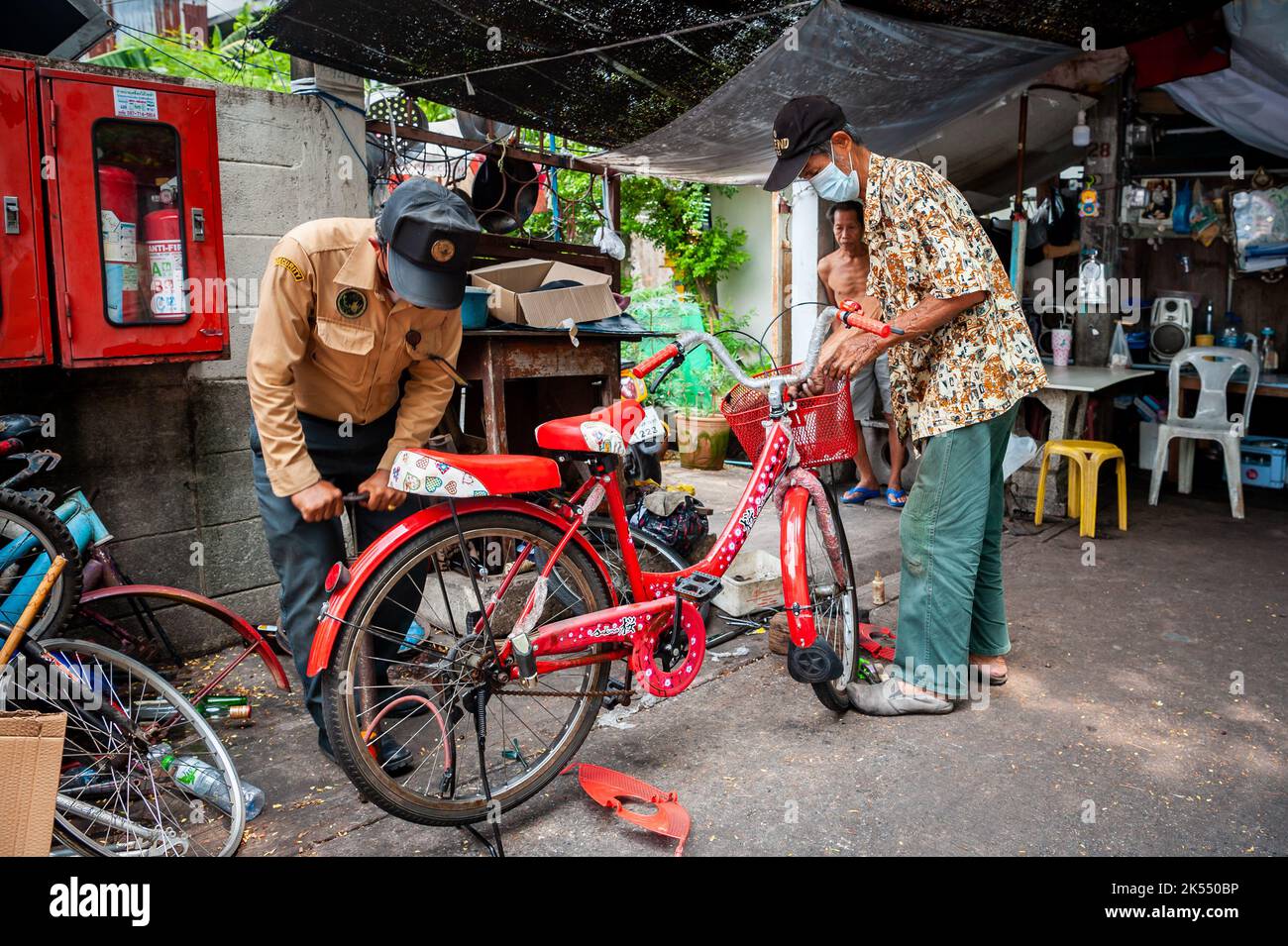 Two Thai men fix their bicycle Stock Photo - Alamy