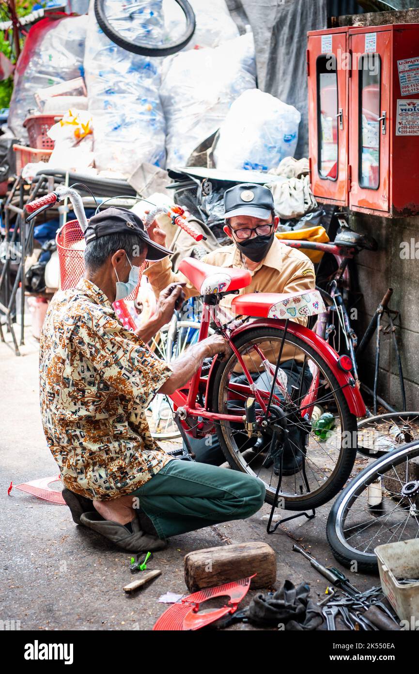 Two Thai men fix their bicycle Stock Photo - Alamy