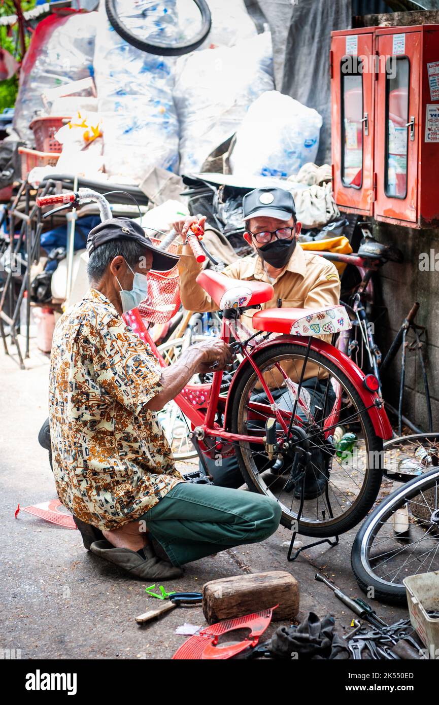 Two Thai men fix their bicycle Stock Photo - Alamy