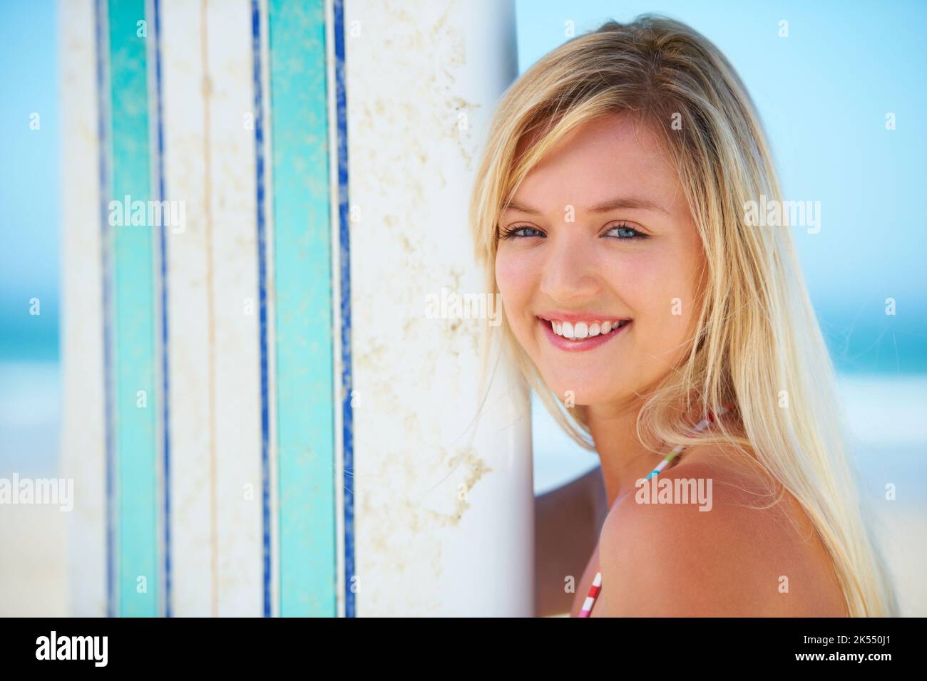 Enjoying the moment. Portrait of a pretty blonde with her surfboard on ...