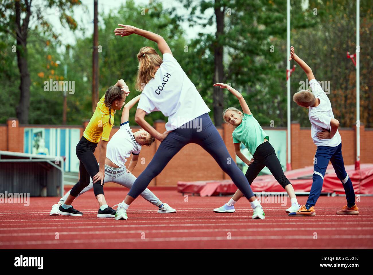 Female coach training athletes. Group of children running on treadmill ... Female coach training athletes. Group of children running on treadmill ...