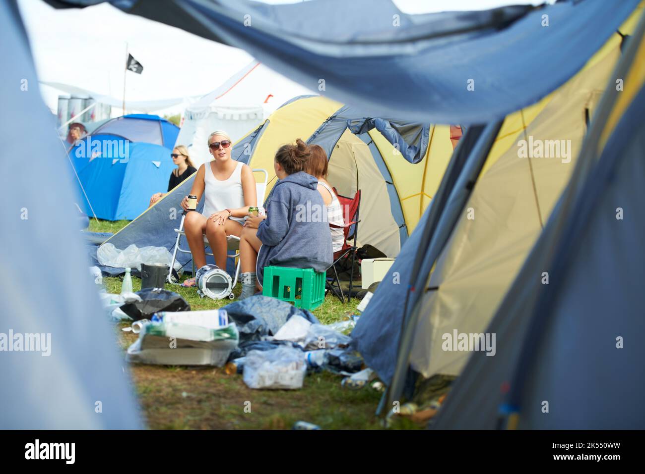 Tent city mess. friends drinking and talking surrounded by tents at an ...