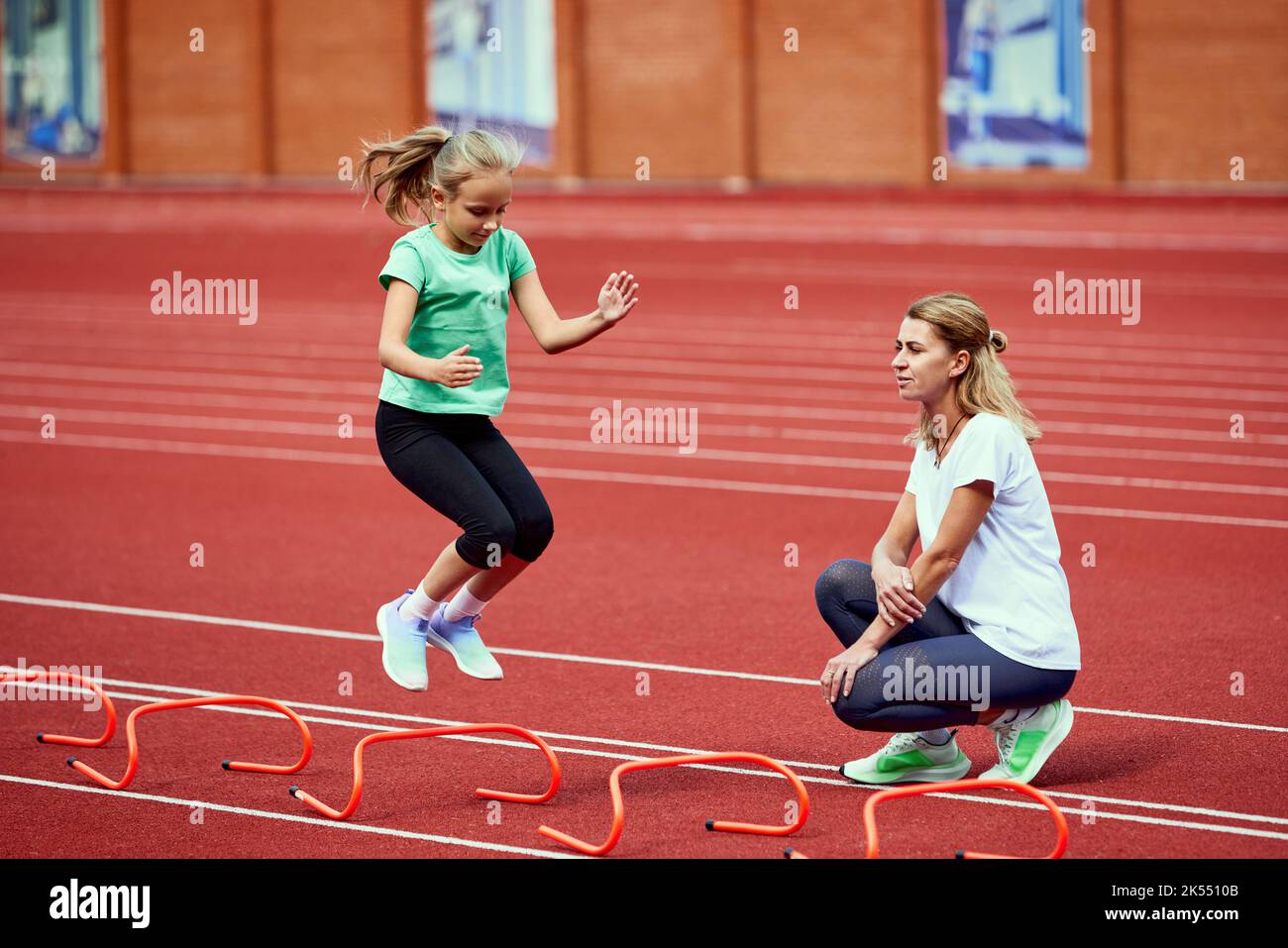 Female coach training athlete. Fit girl getting ready to run on ...