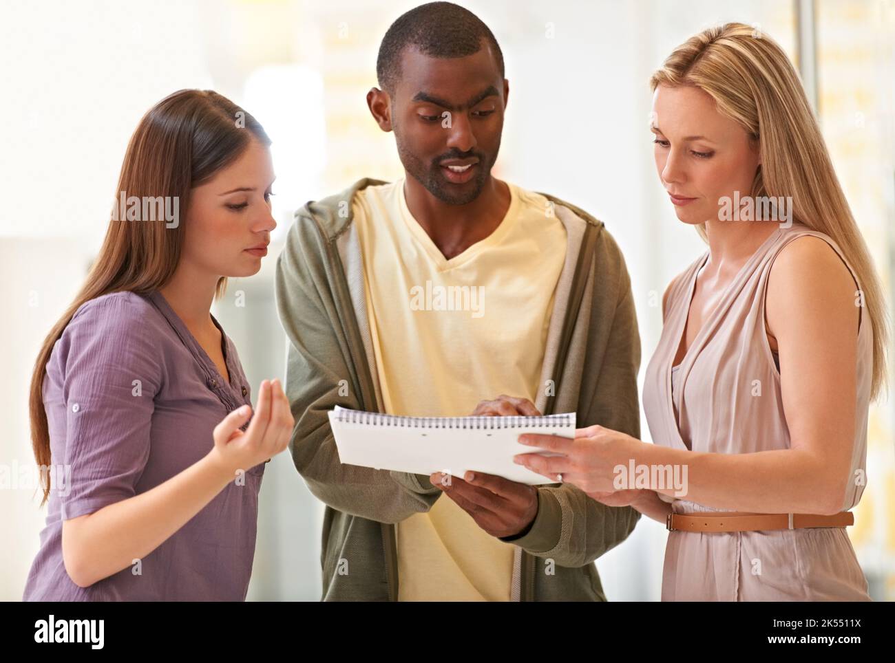 Putting their heads together. three business professionals standing and ...