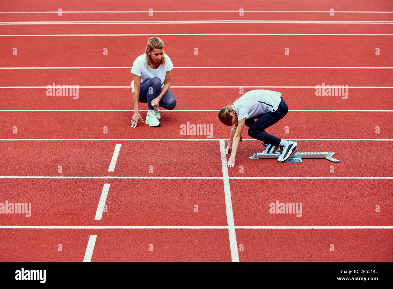 Female coach training athlete. Fit girl getting ready to run on ...