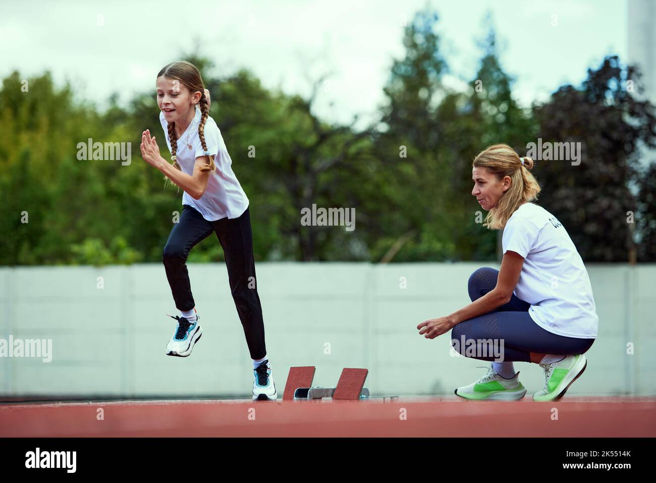Female coach training athlete. Fit girl running on treadmill at the ...