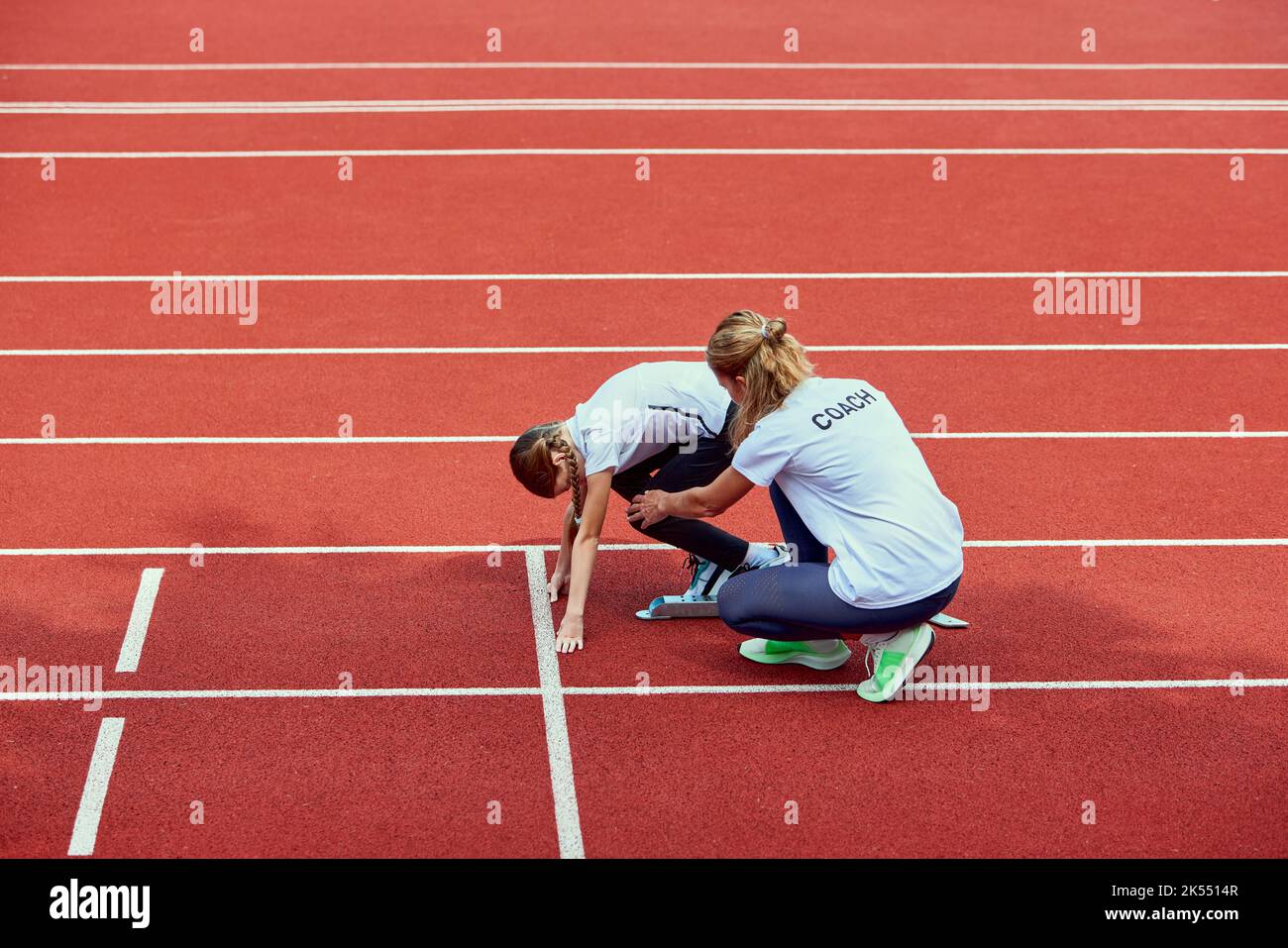 Female coach training athlete. Fit girl getting ready to run on ...
