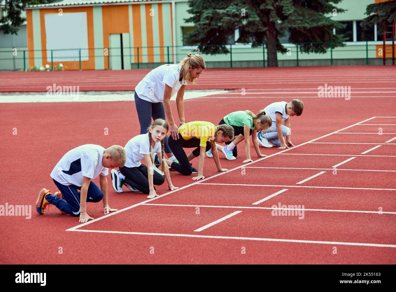 Female coach training athletes. Group of children running on treadmill ...