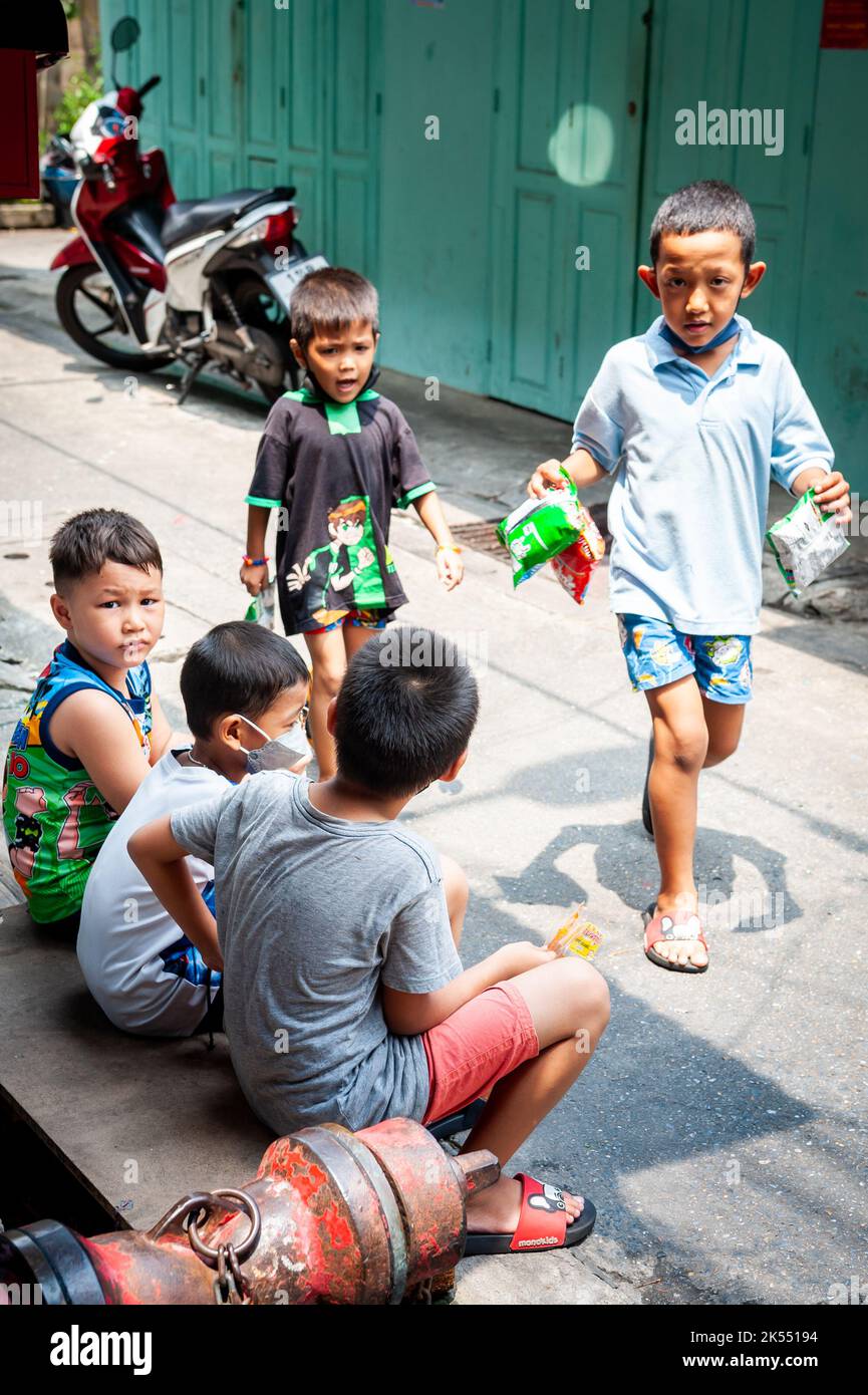 A group of young Thai boys enjoy snacks in the tight streets and lanes ...
