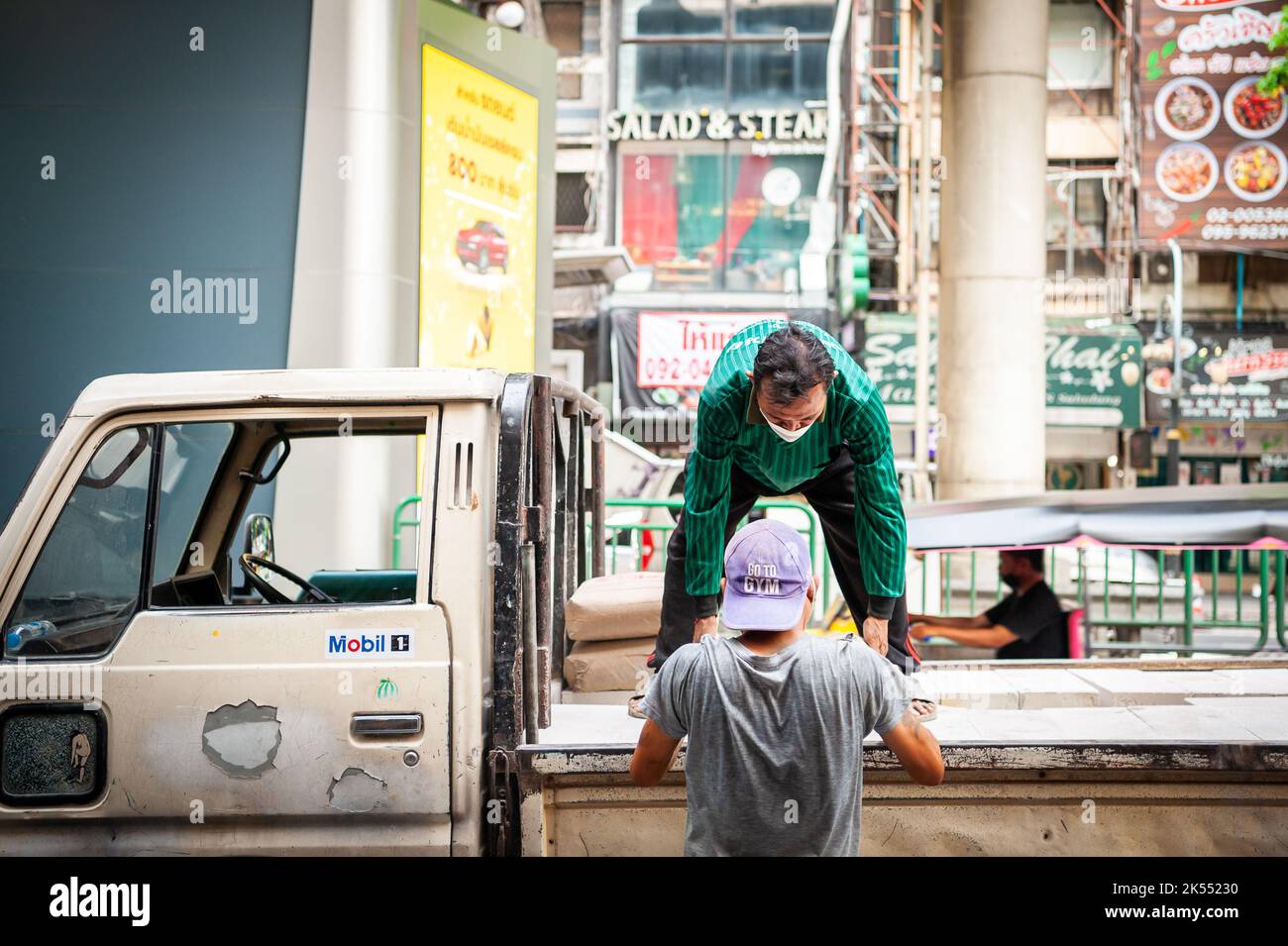 Thai construction workers unload cement or gravel from the back of a ...
