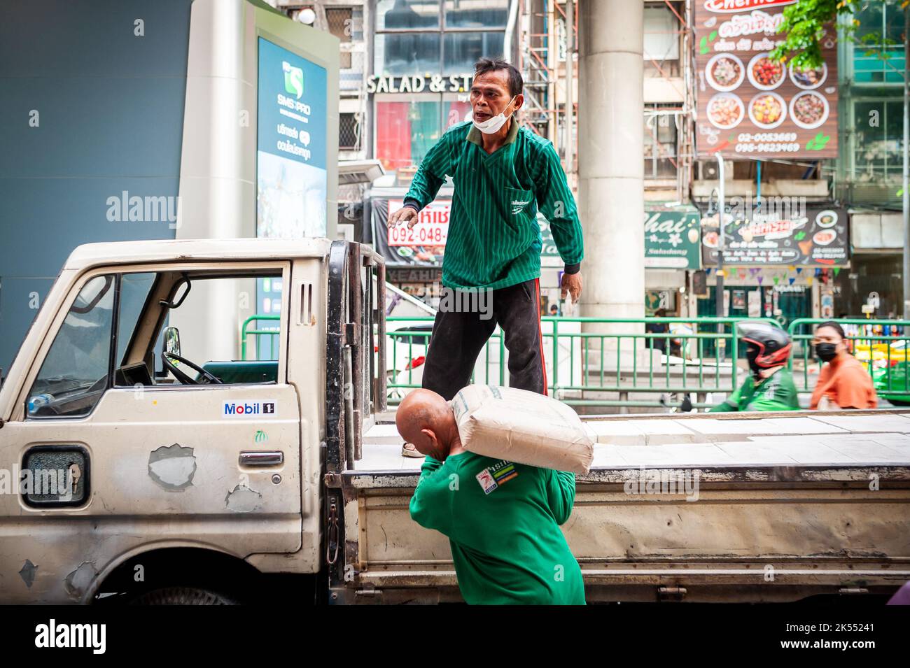 Thai construction workers unload cement or gravel from the back of a ...