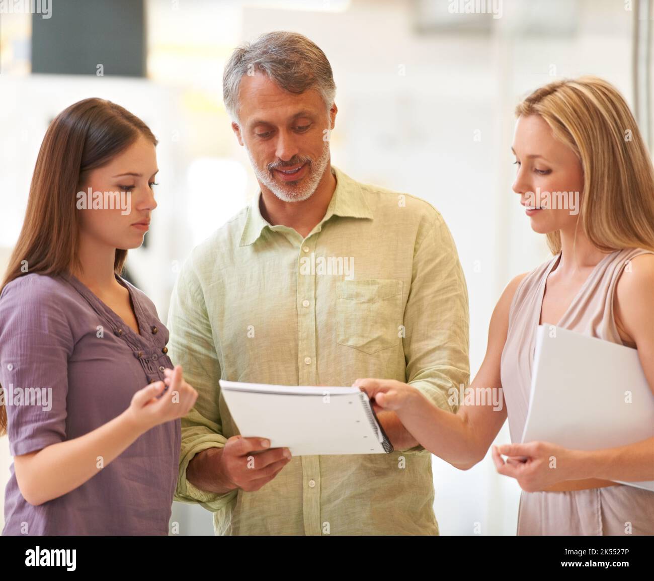Putting their heads together. three business professionals standing and ...