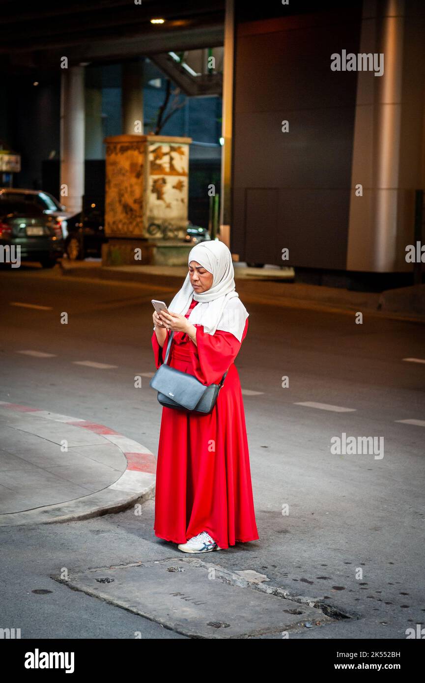 A Thai muslim lady stands on Sukhumvit Rd, Bangkok, Thailand using her ...