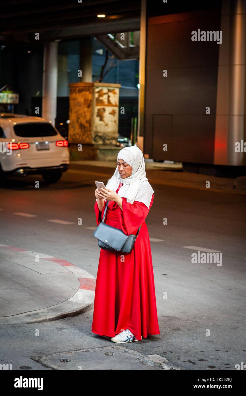 A Thai muslim lady stands on Sukhumvit Rd, Bangkok, Thailand using her ...