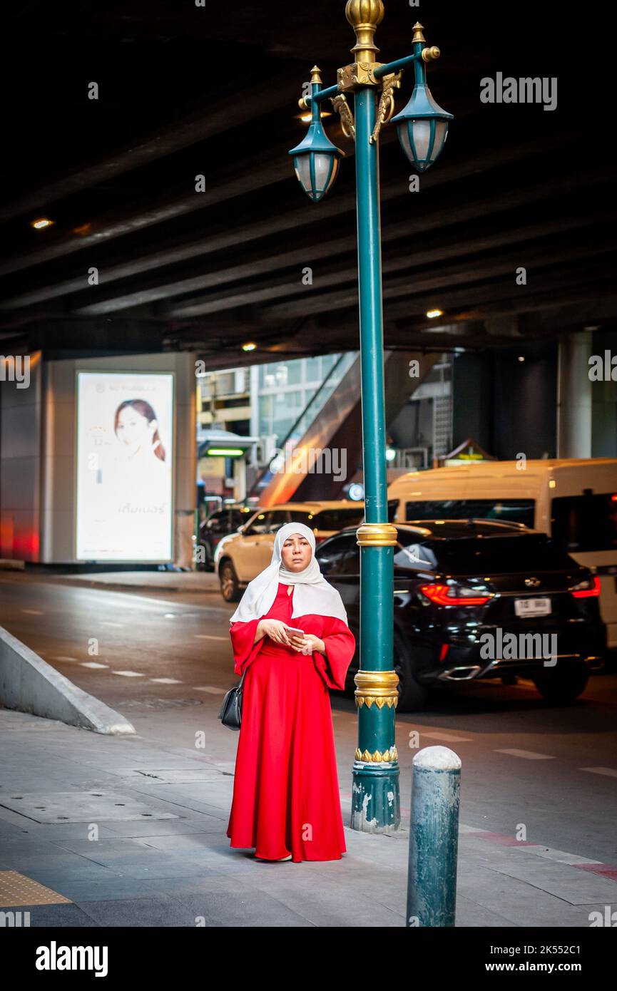 A Thai muslim lady stands on Sukhumvit Rd, Bangkok, Thailand using her ...