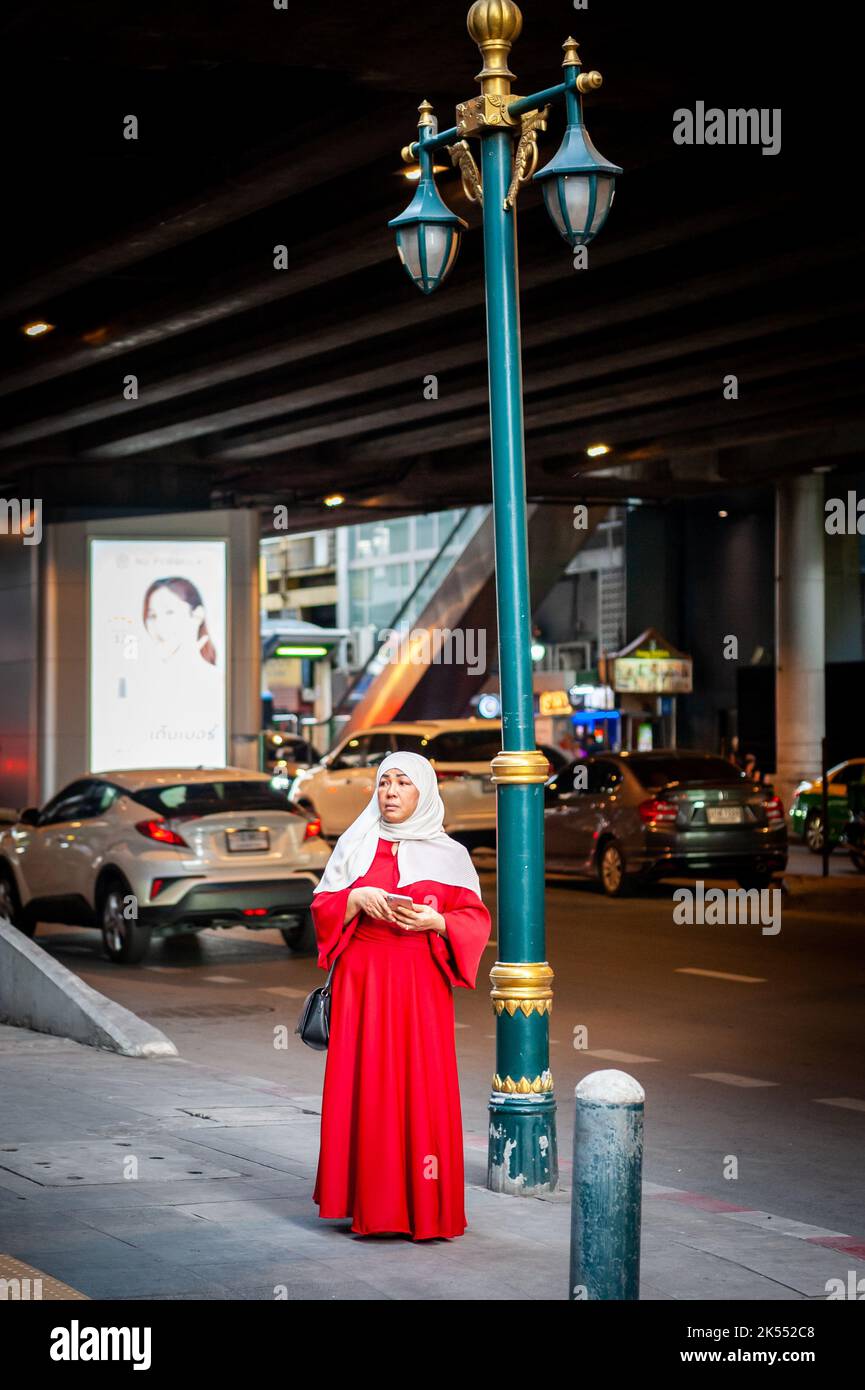 A Thai muslim lady stands on Sukhumvit Rd, Bangkok, Thailand using her ...