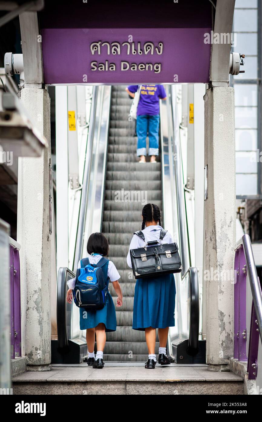 Thai school girls leaving school ascend the escalator at the BTS sky ...