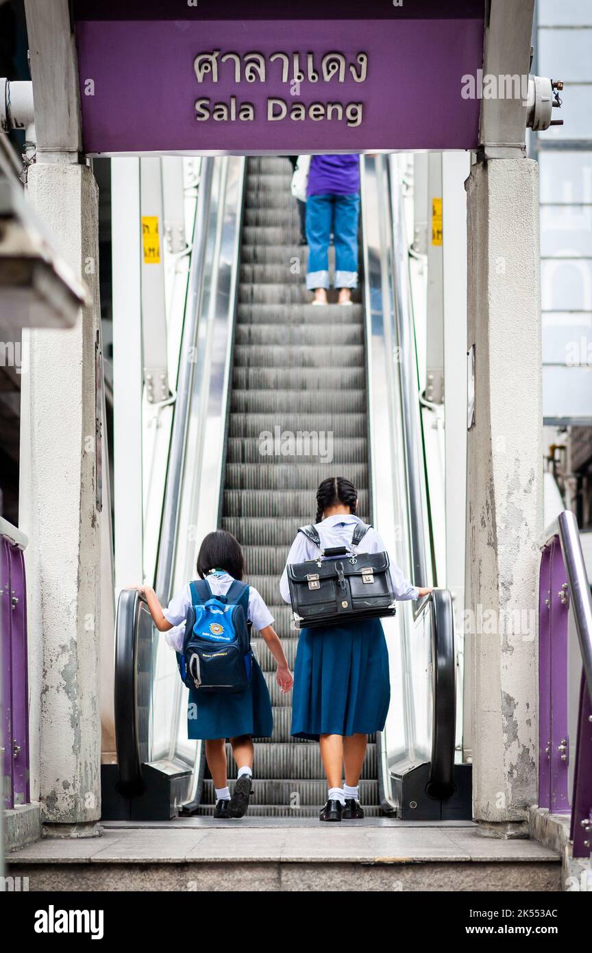 Thai school girls leaving school ascend the escalator at the BTS sky ...