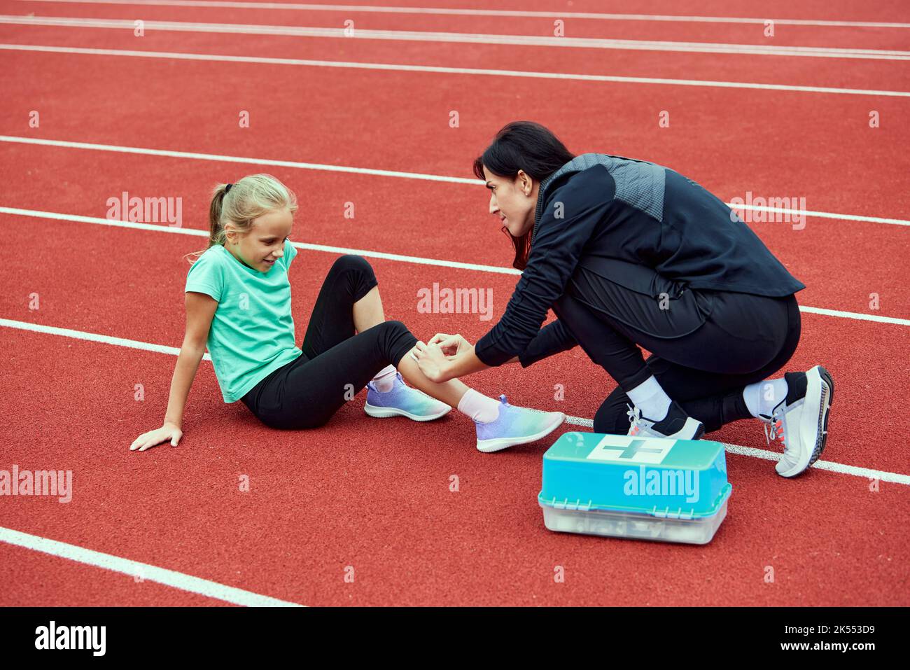 First aid for a young athlete at stadium. Sport teen girl suffering ...