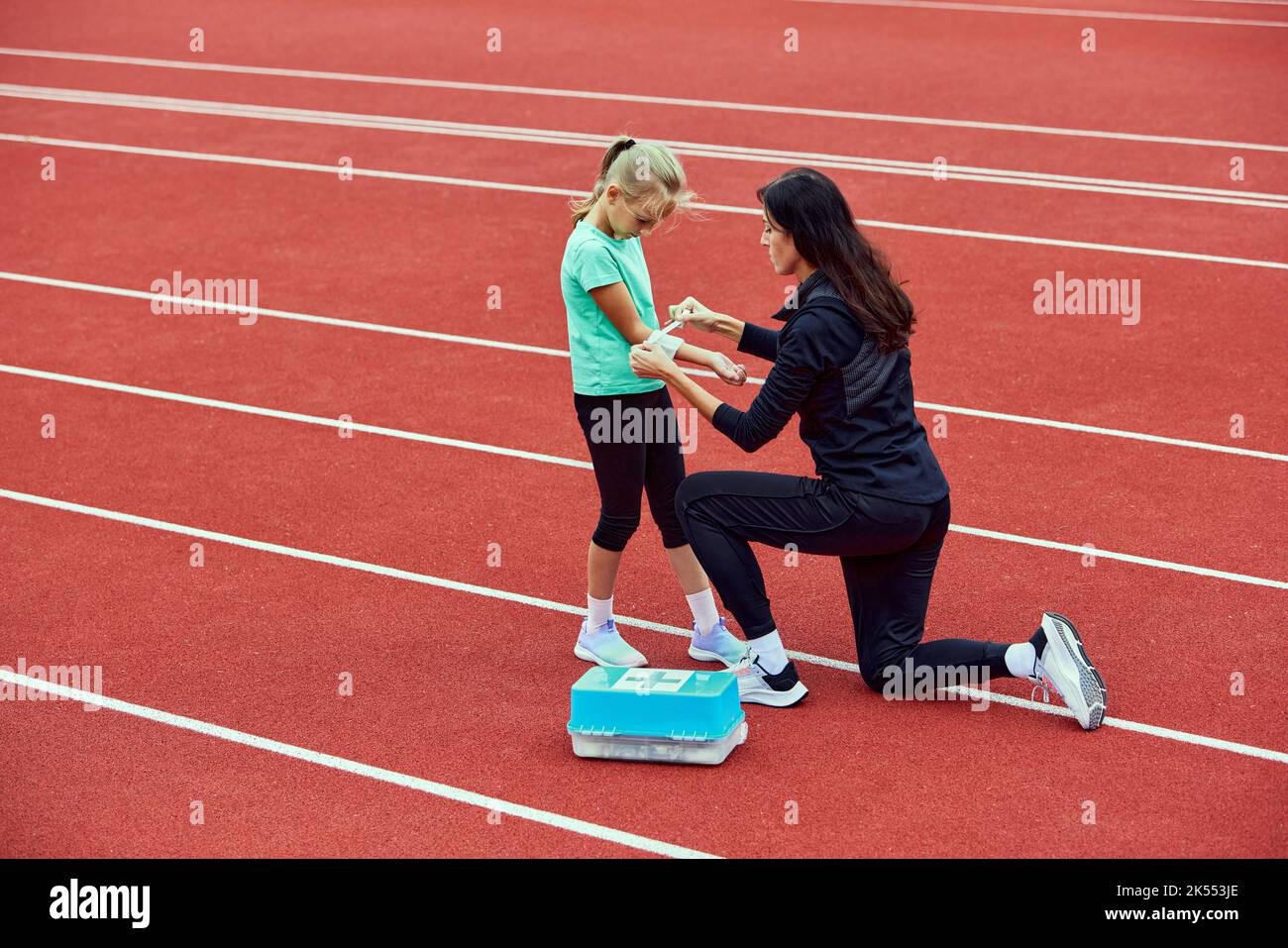 First aid for a young athlete at stadium. Sport teen girl suffering ...