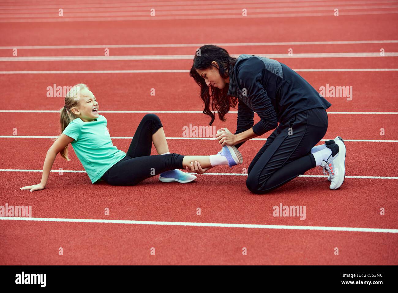 First aid for a young athlete at stadium. Sport teen girl suffering ...