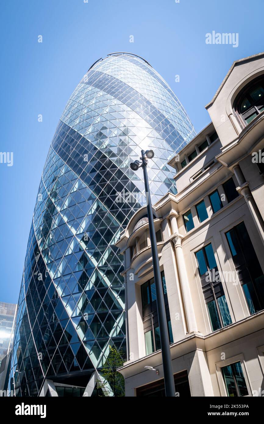 The glass Gherkin Building looms up and shines bright from the street ...