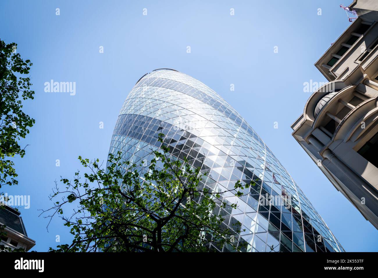 The glass Gherkin Building looms up and shines bright from the street ...