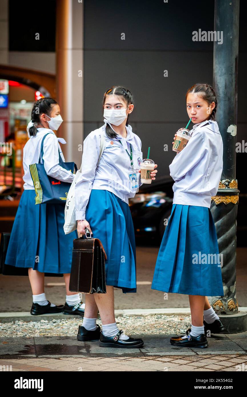 A group of young Thai schoolgirls wait for the bus at the end of the ...
