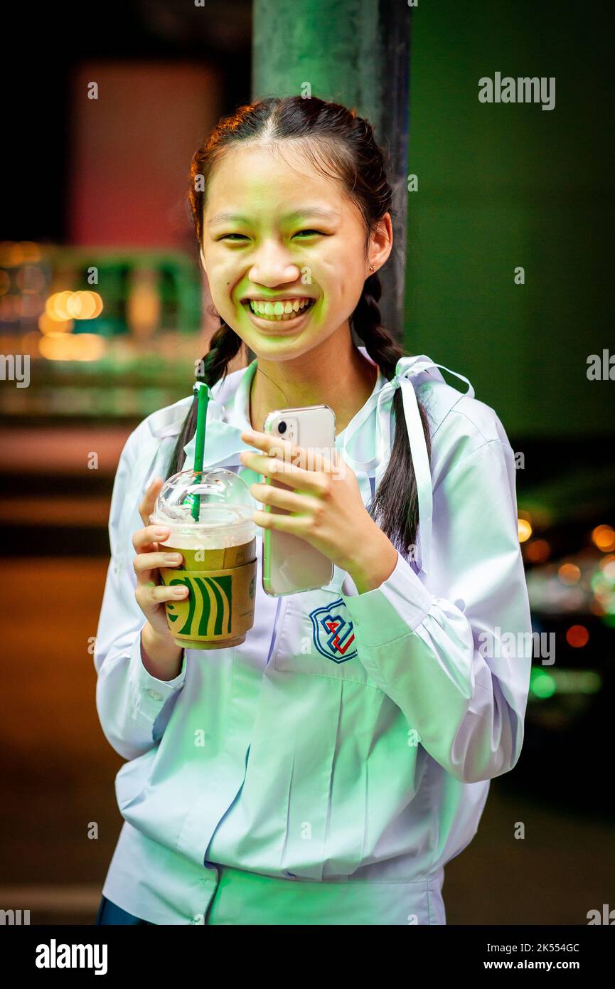 A beautiful Thai school girl poses and laughs holding her Starbucks ...