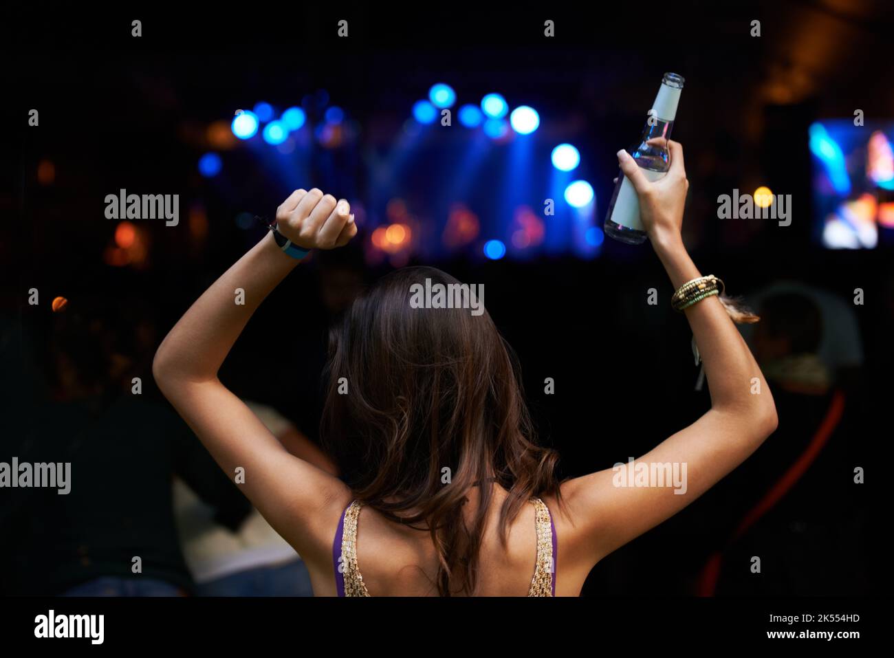 Letting the music take her away. Rear view of a woman partying to a ...
