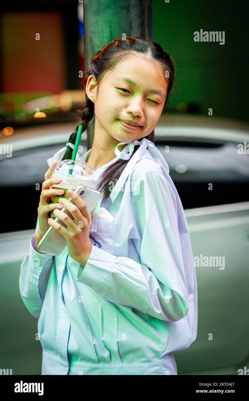 A beautiful Thai school girl poses and laughs holding her Starbucks ...