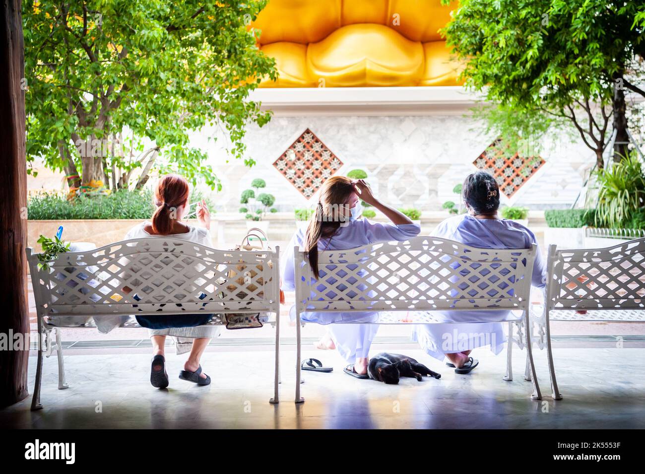 The giant golden Buddha looms large above three Thai ladies sat ...