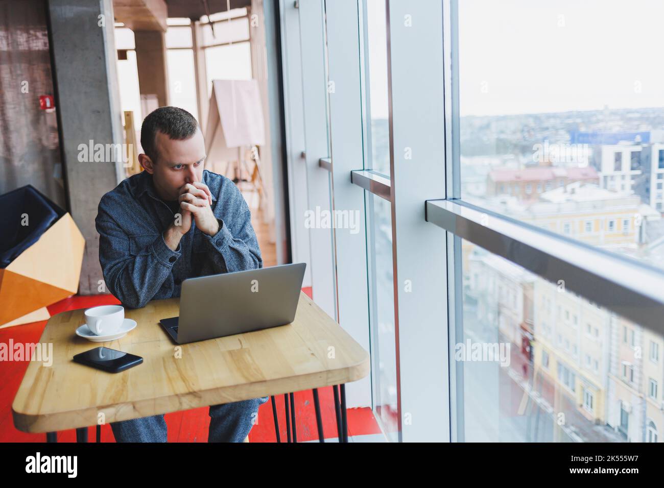 A young successful businessman in a suit drinks coffee and works in a ...
