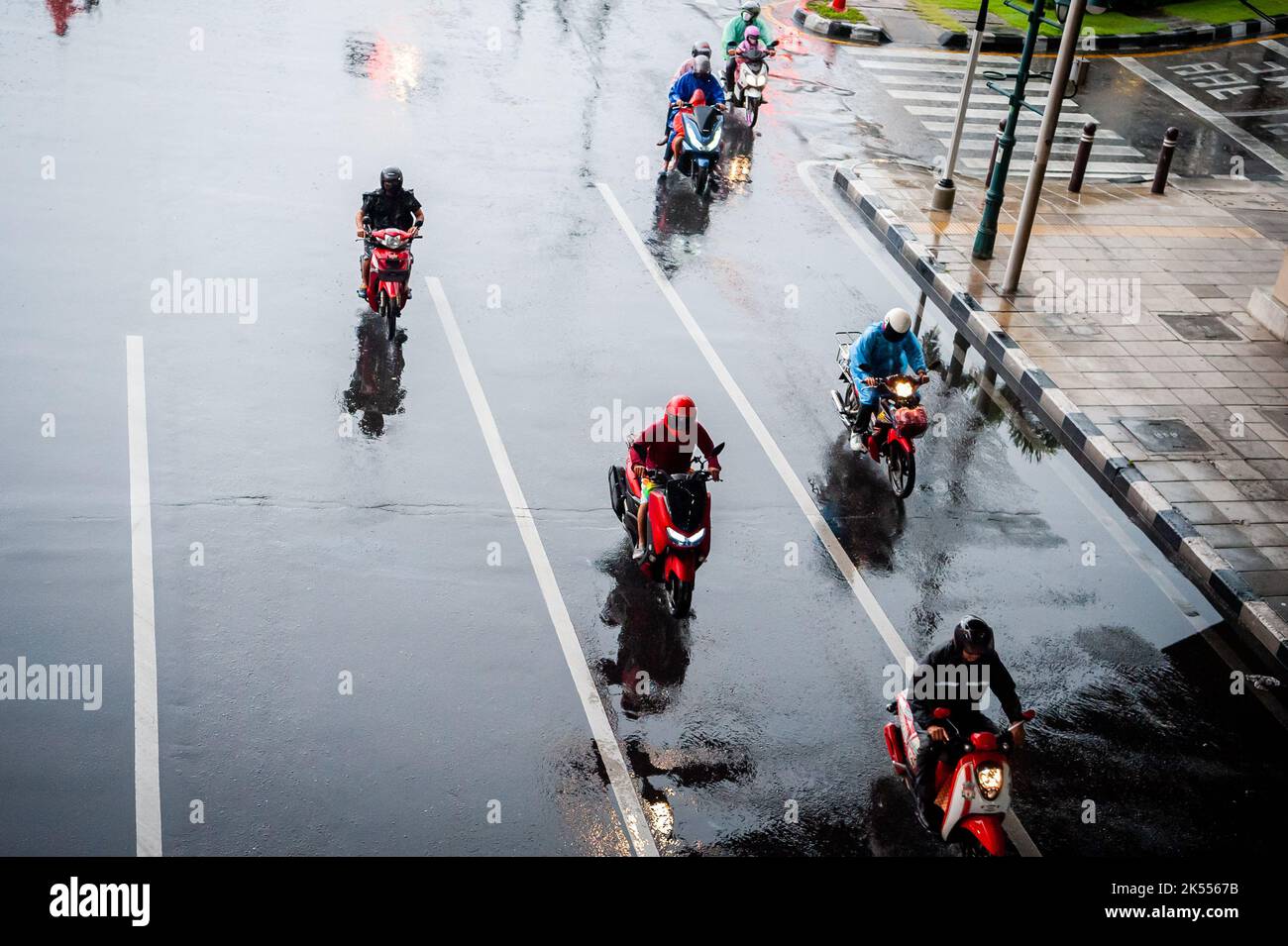 Cars, vans, buses and motorbikes all pass along a busy intersection on ...