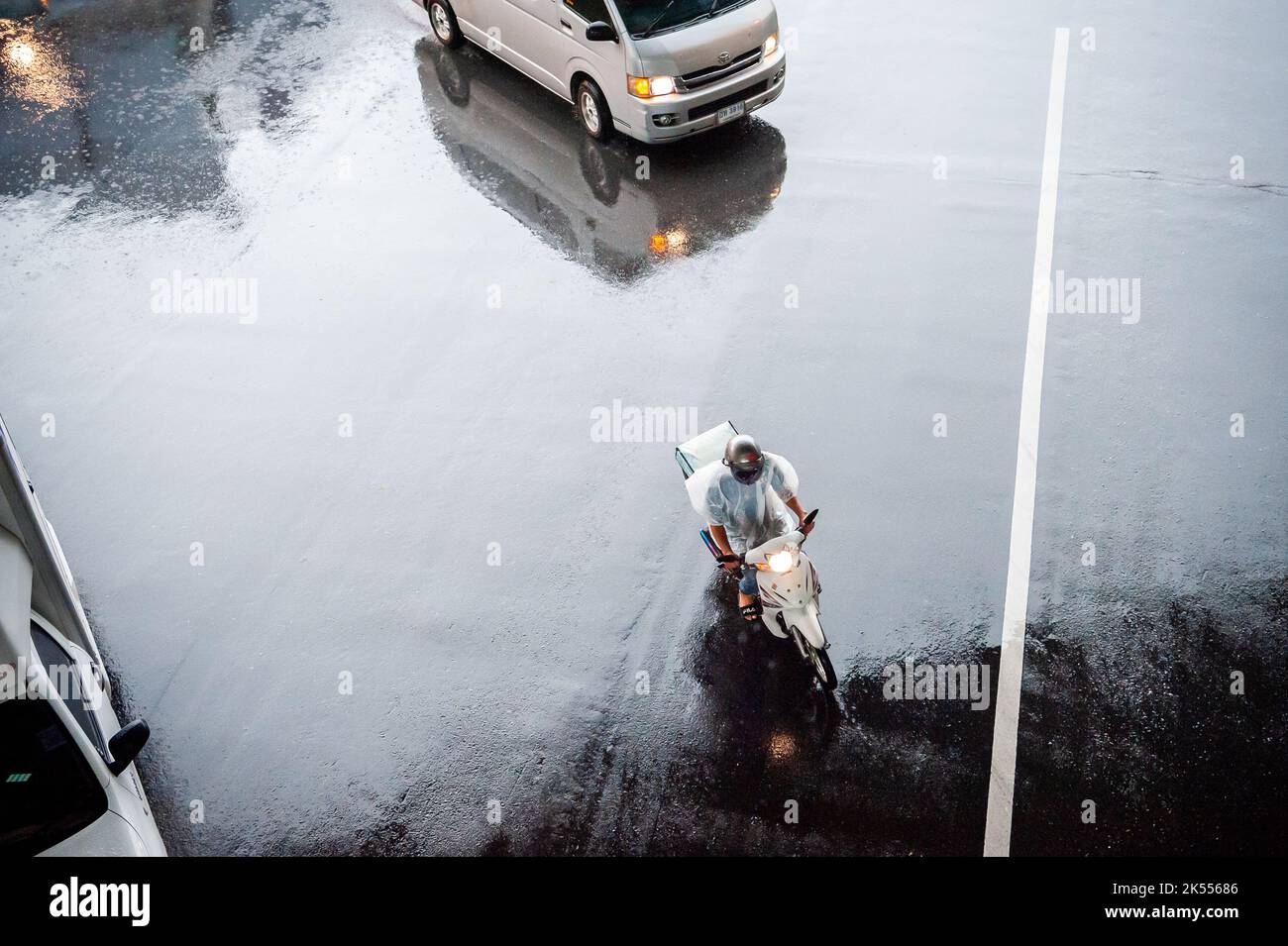 Cars, vans, buses and motorbikes all pass along a busy intersection on ...