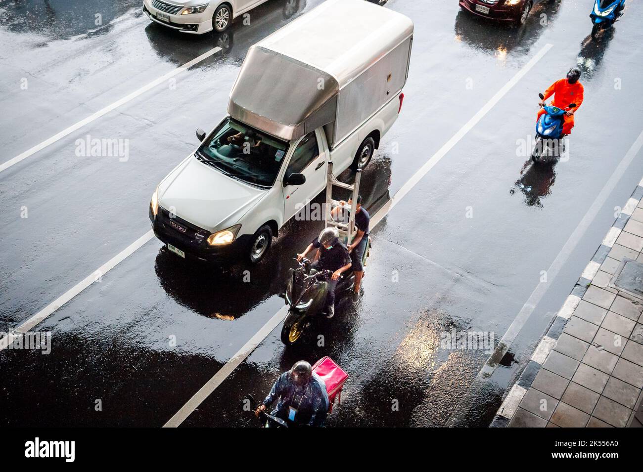 Cars, vans, buses and motorbikes all pass along a busy intersection on ...