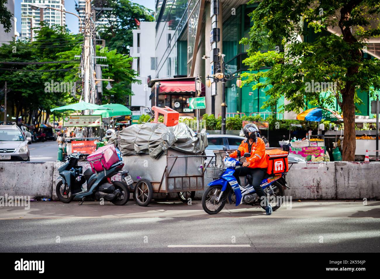 Delivery motorbike riders pause and move on from the centre of the road ...