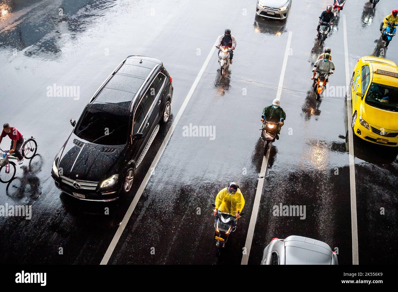 Cars, vans, buses and motorbikes all pass along a busy intersection on ...