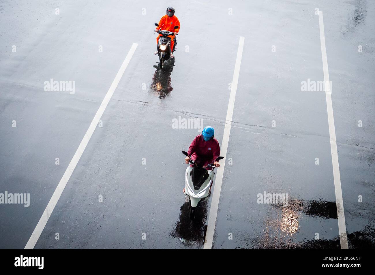 Cars, vans, buses and motorbikes all pass along a busy intersection on ...