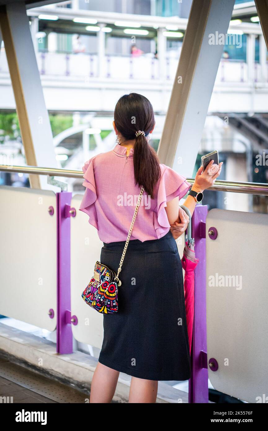 A young Thai lady pauses in thought on the sky walk above the busy ...