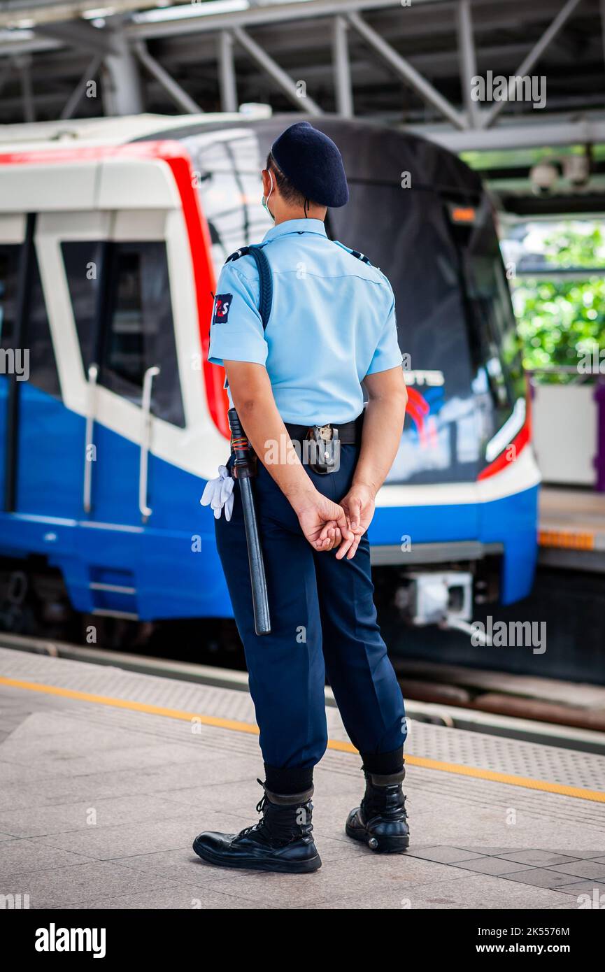 A smart Thai train guard watches the public and trains on the platform ...
