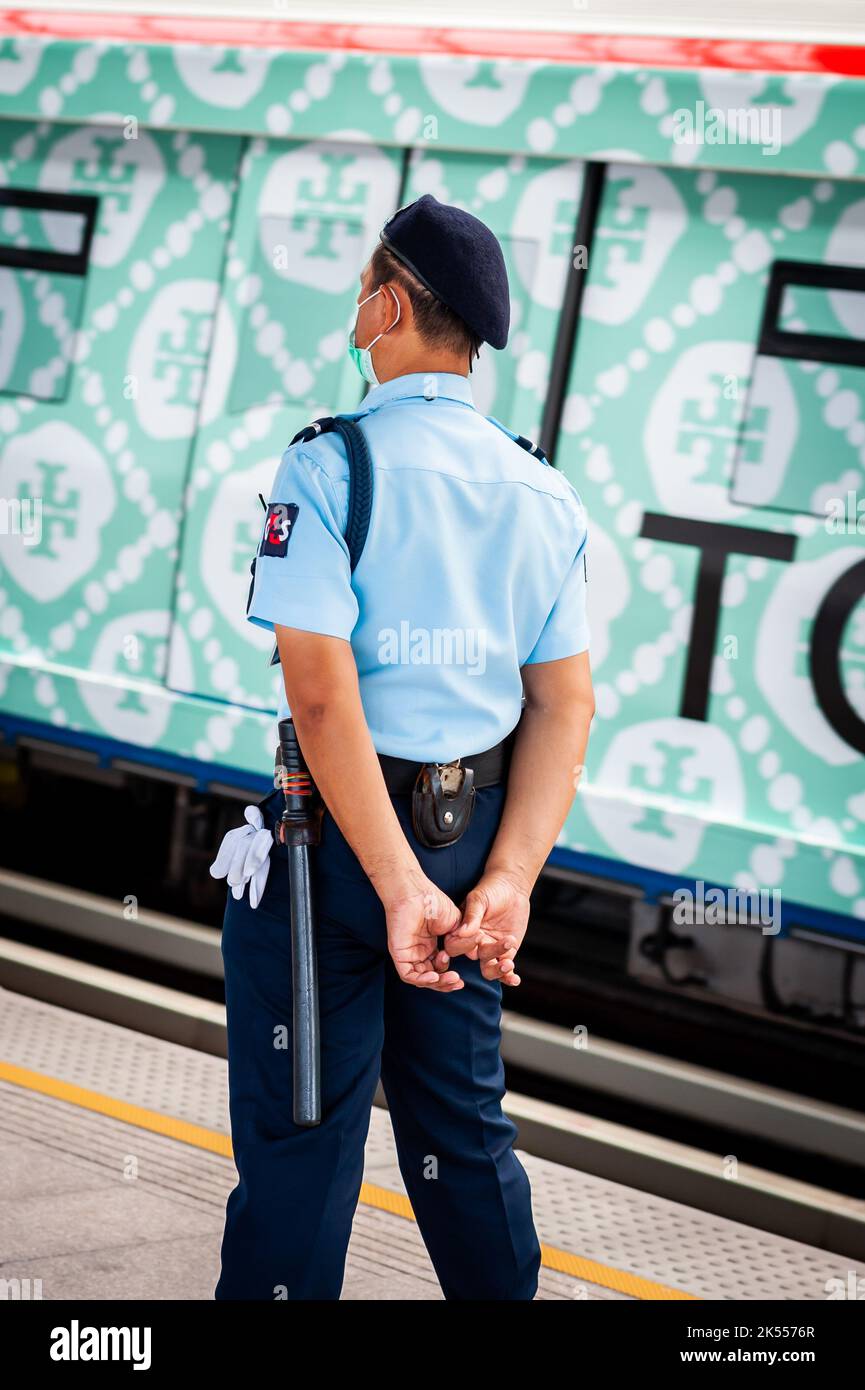 A smart Thai train guard watches the public and trains on the platform ...